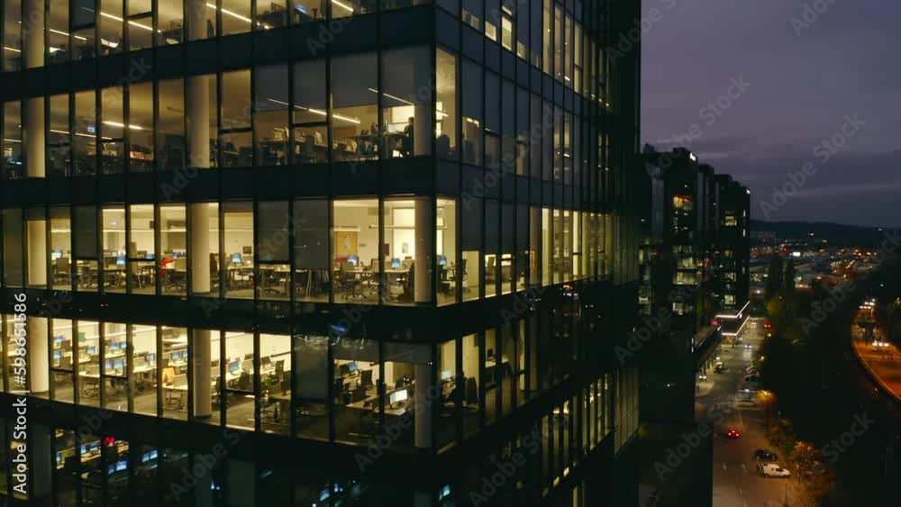 Aerial view of corporate office windows with workers at night ...