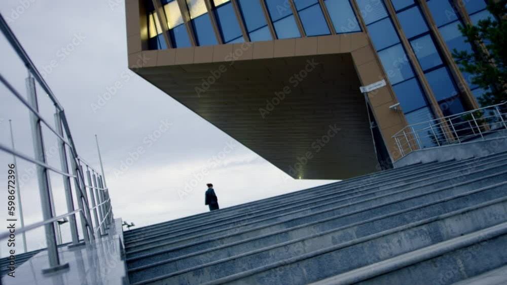 Woman enters office building with modern facade walking up concrete ...