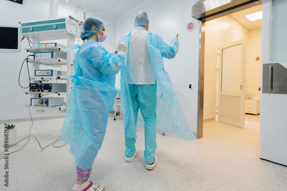 The nurse helps the surgeon put on a sterile gown before surgery ...