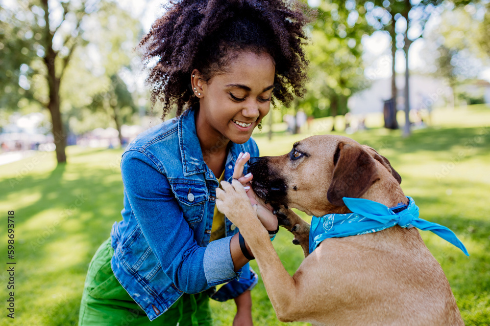 Multiracial girl sitting and resting with her dog outside in the park ...