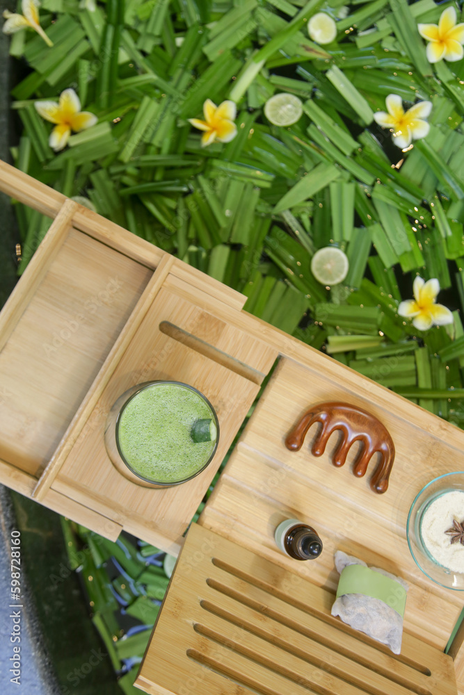 Tub full of water and herbs with wooden bathtub tray with various ...