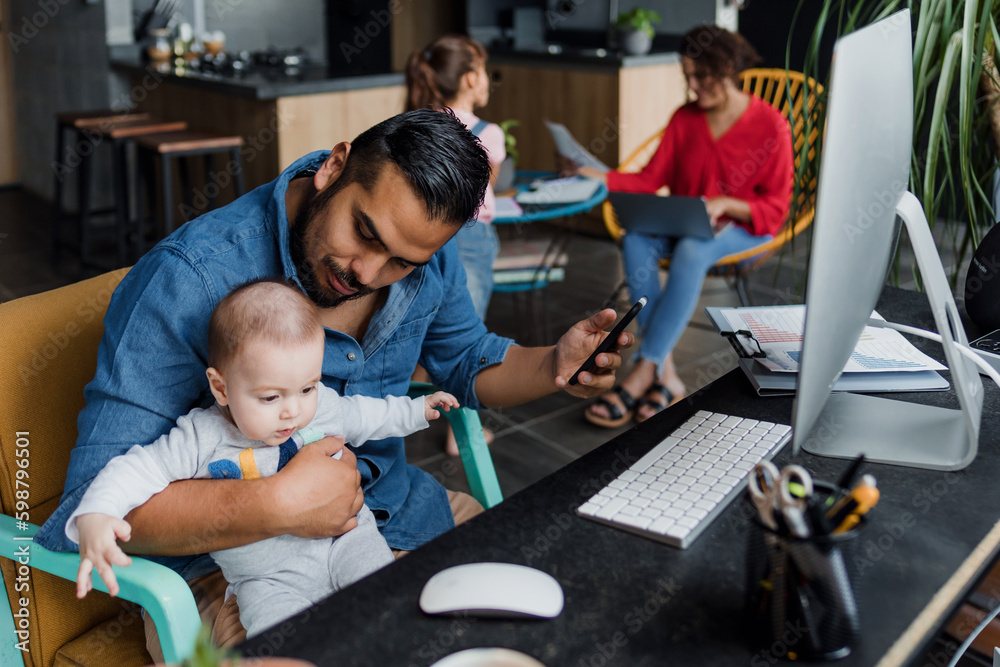 latin father using computer and working at home while he take care of ...