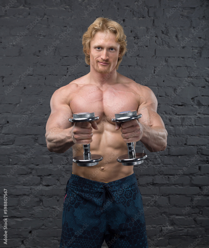 Muscular bodybuilder man. Man with large muscles of the body on a gray ...