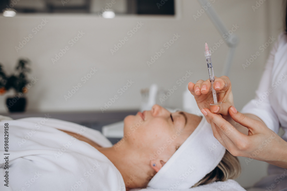 Beautician doctor with botulinum toxin syringe making injection to to ...