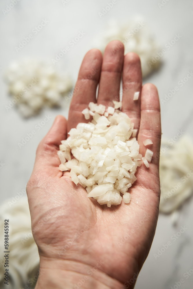 Small diced or finely chopped onions on mans hand. Photo show how does ...