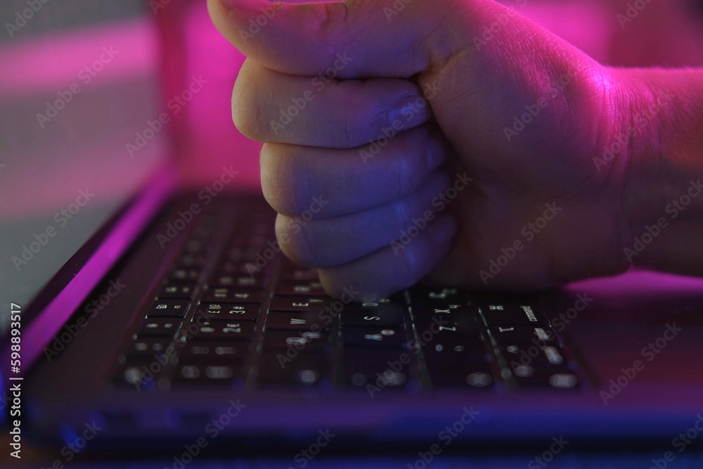Human fist bump on the keyboard of laptop. Neon pink blue light ...