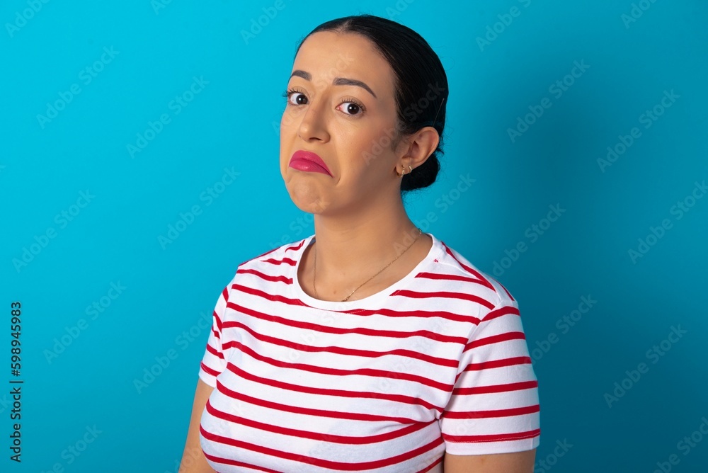 beautiful woman wearing striped T-shirt over blue studio background ...