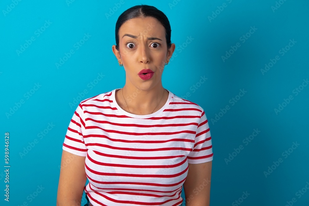 beautiful woman wearing striped T-shirt over blue studio background ...