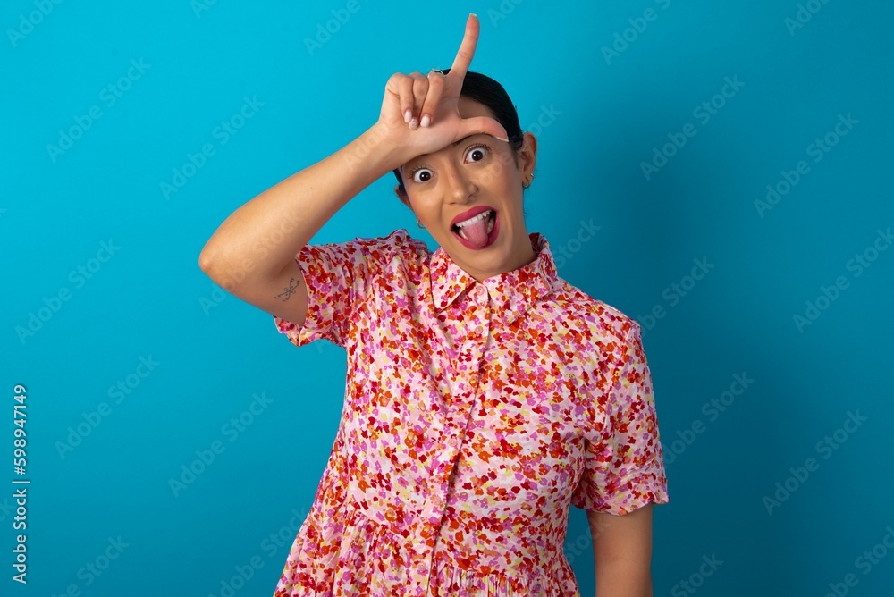 beautiful woman wearing floral dress over blue studio background ...