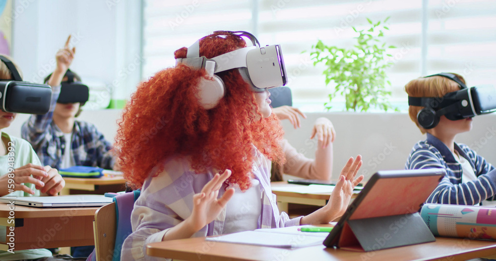 Little Caucasian girl pupil with red ginger curly hair in VR headset ...