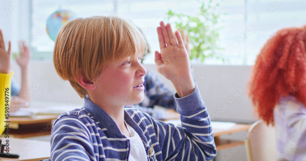 Cute boy in casual wear raising hand and answering teacher's question ...