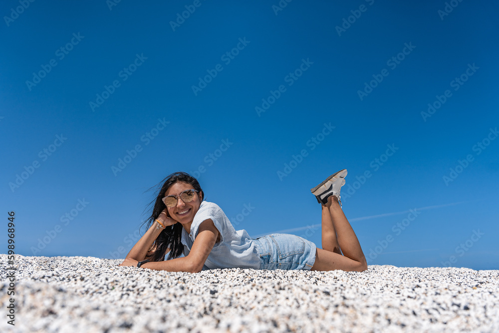 mujer latina acostada boca abajo en arena blanca con cielo azul de ...
