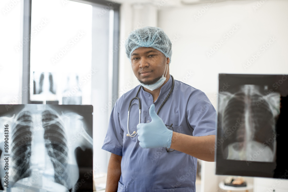 Friendly multiracial male in scrub top and latex gloves giving thumb-up ...