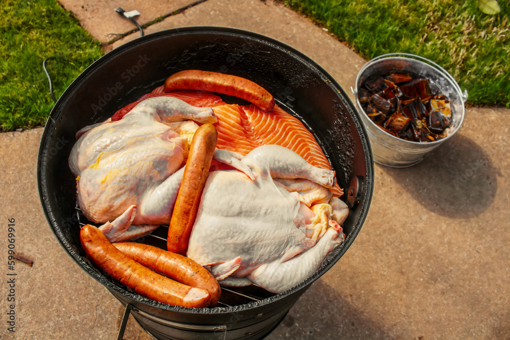 Raw food loaded into a barrel electric smoker with wood soaking ...