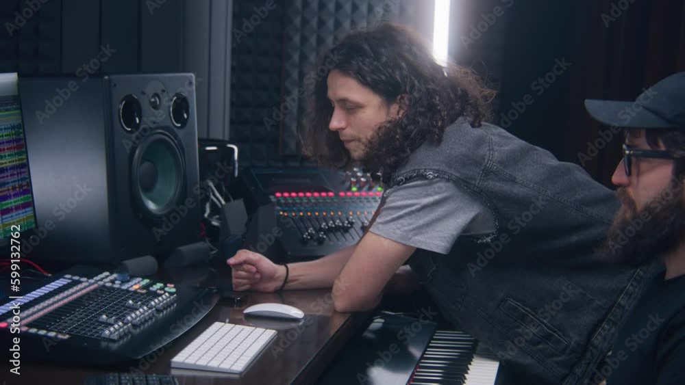 Audio engineer and male singer create song in music recording room ...