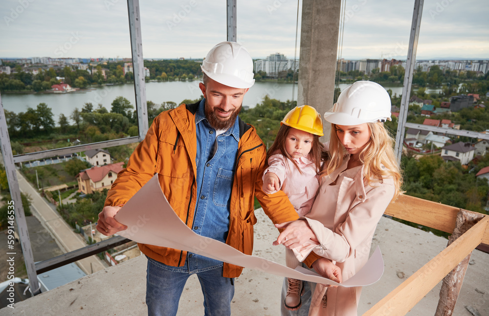 Parents with daughter studying architectural drawings in apartment ...