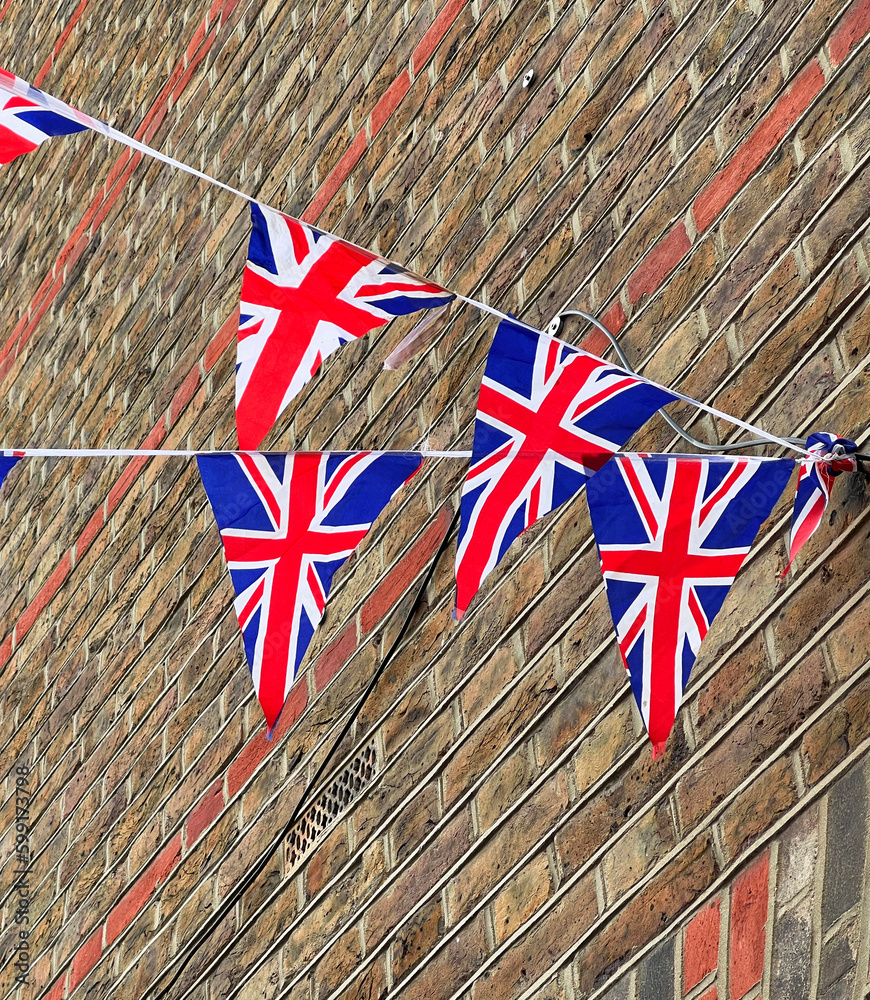 British Union Jack flags hanging at the street against brick wall ...