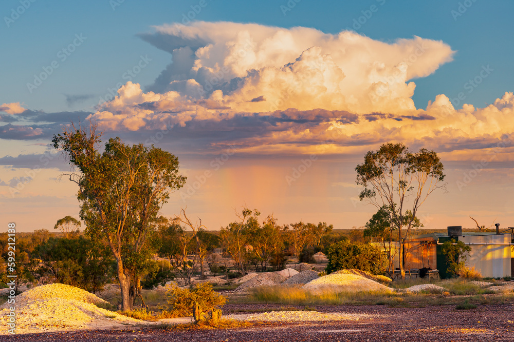 Rain falling from a large thunderstorm over an outback mining landscape ...