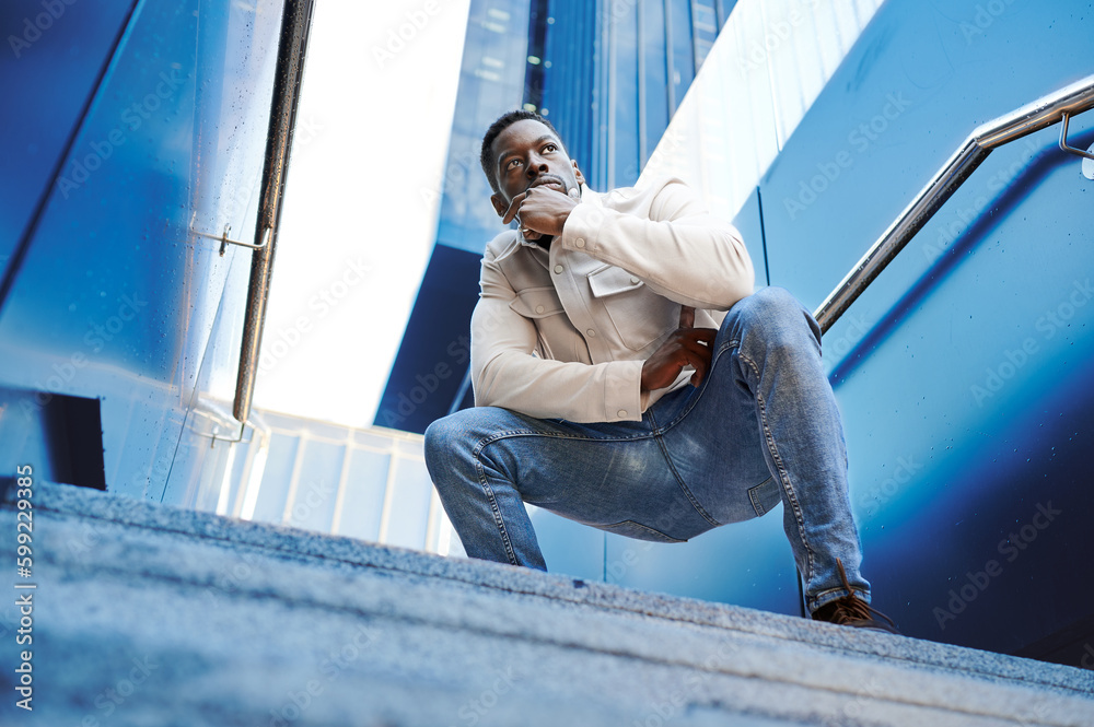 Handsome African man posing proud crouching gesturing on a staircase in ...