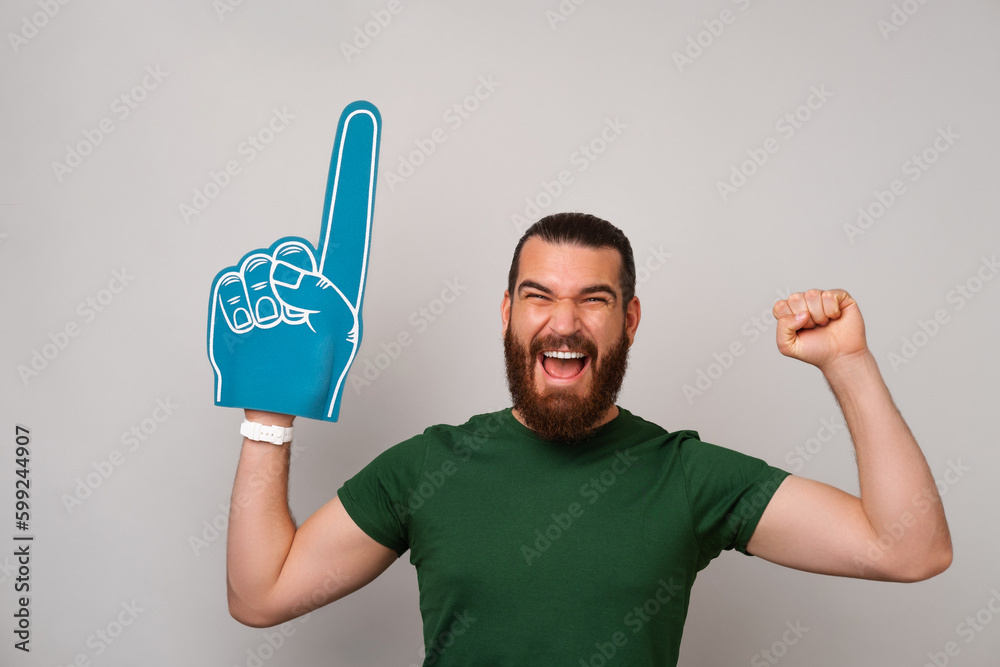 Excited man wearing foam finger fan glove while making the winner ...