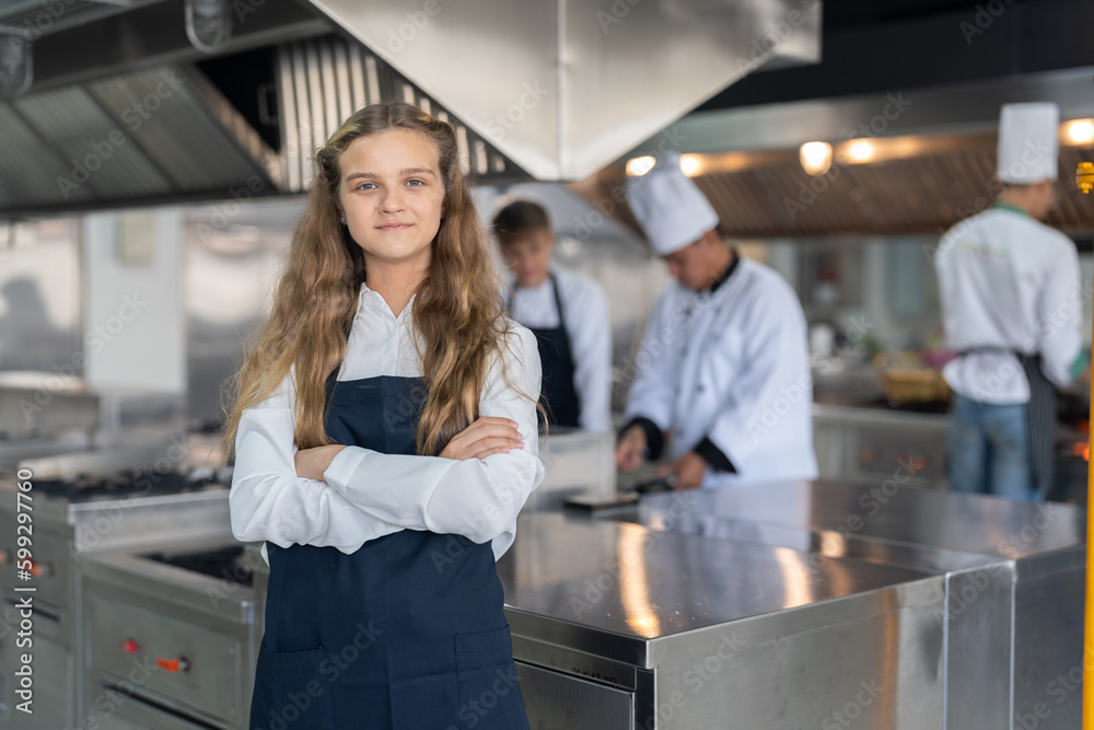 Portrait of student girl chef wearing apron standing with crossed arms ...
