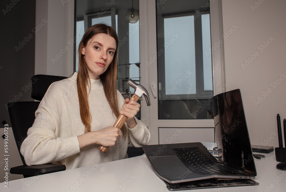A woman with a hammer wants to break a laptop. Failure at work. Hard ...