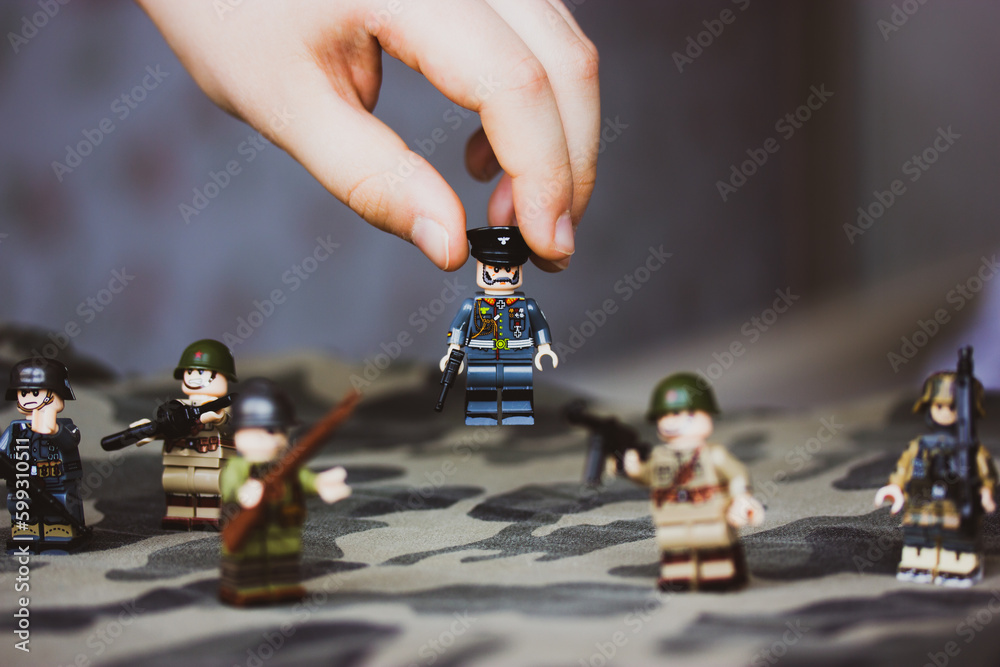 Kyiv, Ukraine. March 9, 2022. Figurine of officer in child's hand. A ...