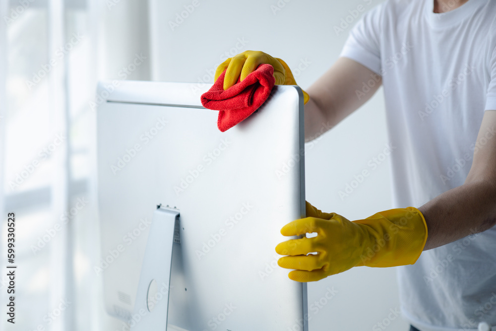 Person cleaning room, cleaning worker is using cloth to wipe computer ...
