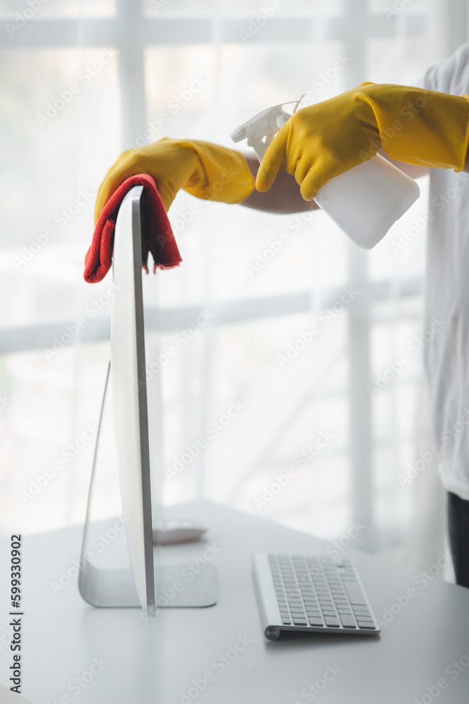Person cleaning room, cleaning worker is using cloth to wipe computer ...