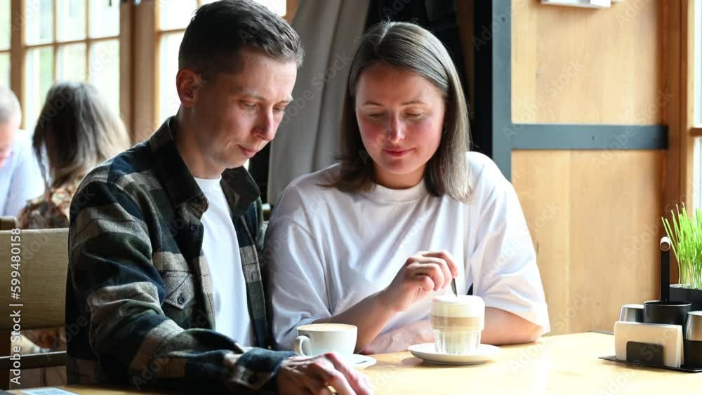 Sitting by a bright window in a cozy restaurant, a couple shares a meal ...