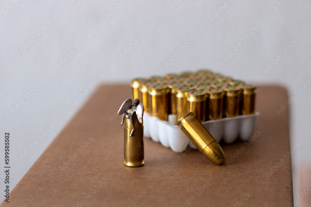 Metallic angel climbing on a 9mm parabellum cartridge or bullet ภาพถ่าย ...