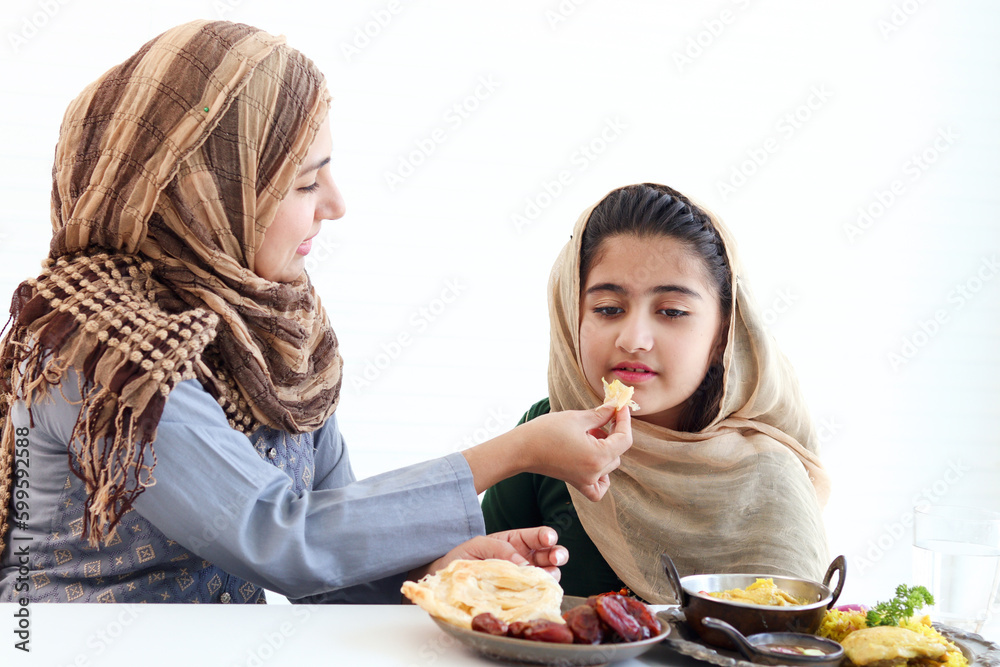 Adorable Muslim happy girl sits at kitchen table, kid with hijab enjoy ...
