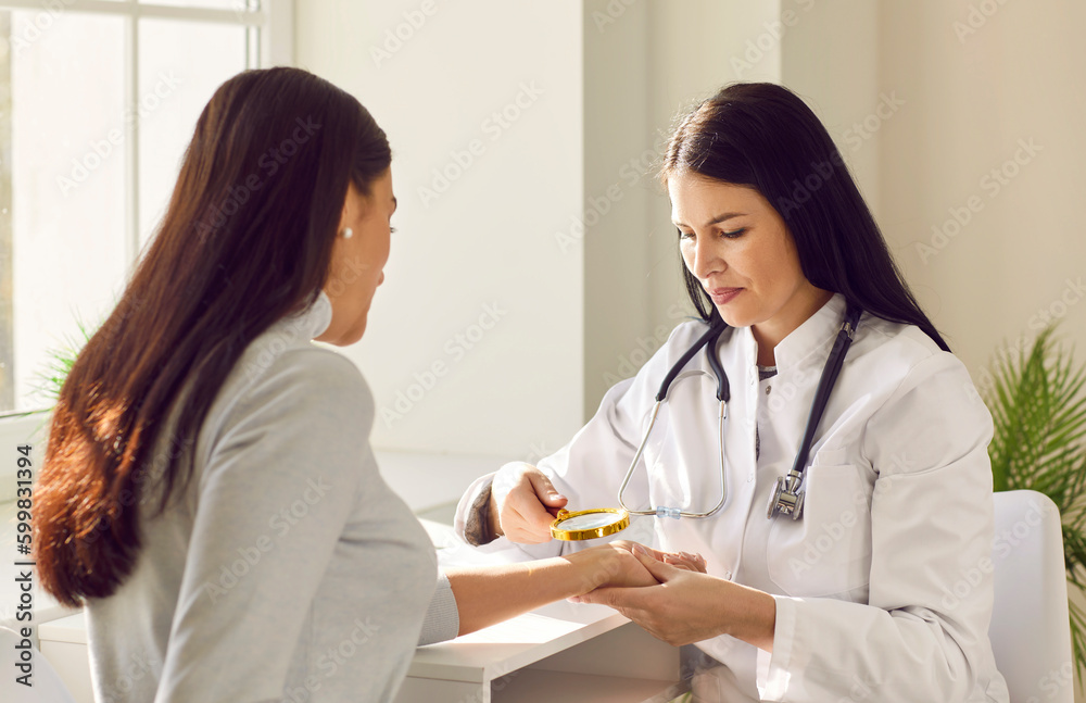 Female friendly doctor examining hand skin of young woman patient ...