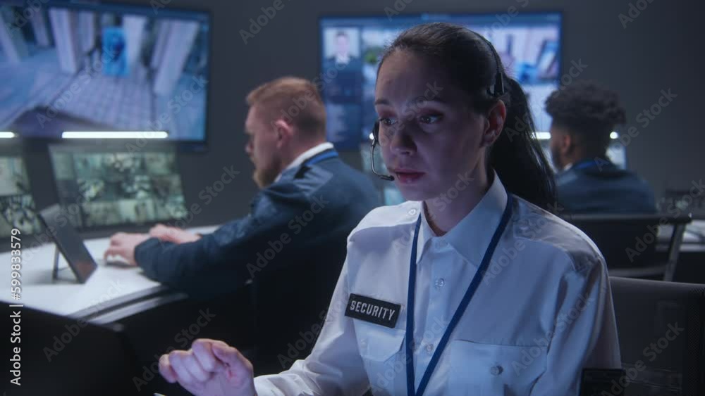 Close up shot of female security operator in headset looking at ...