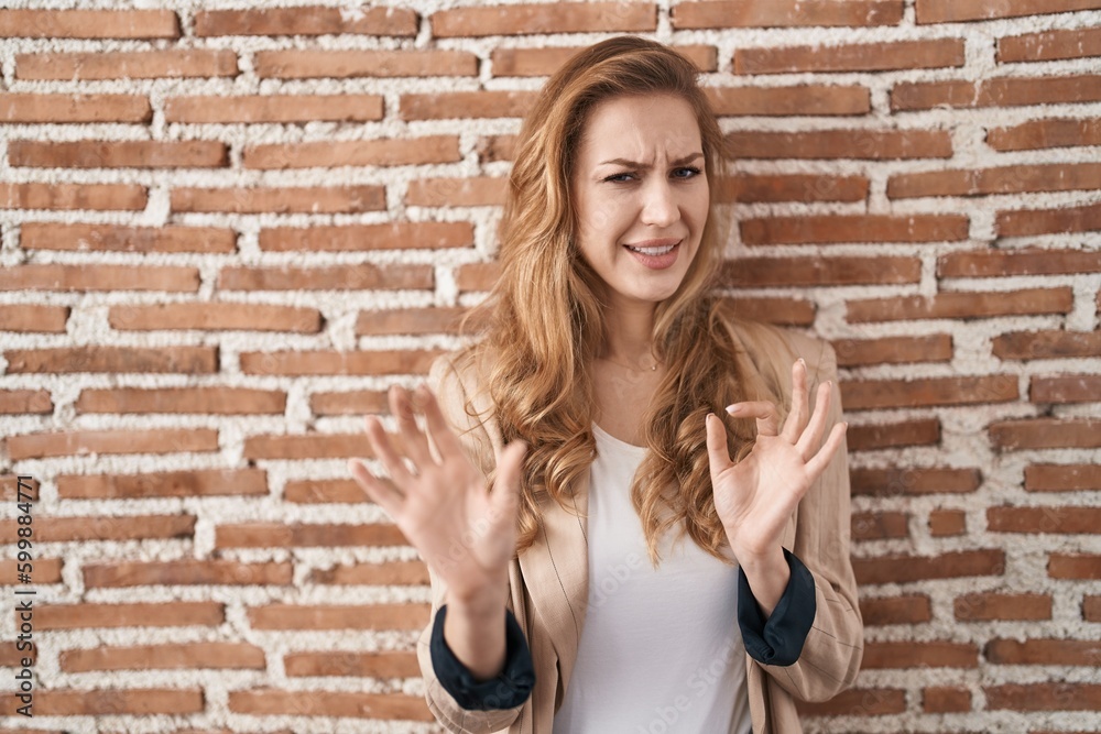Beautiful blonde woman standing over bricks wall disgusted expression ...