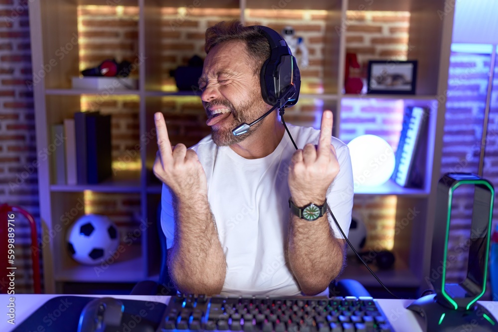 Middle age man with beard playing video games wearing headphones ...