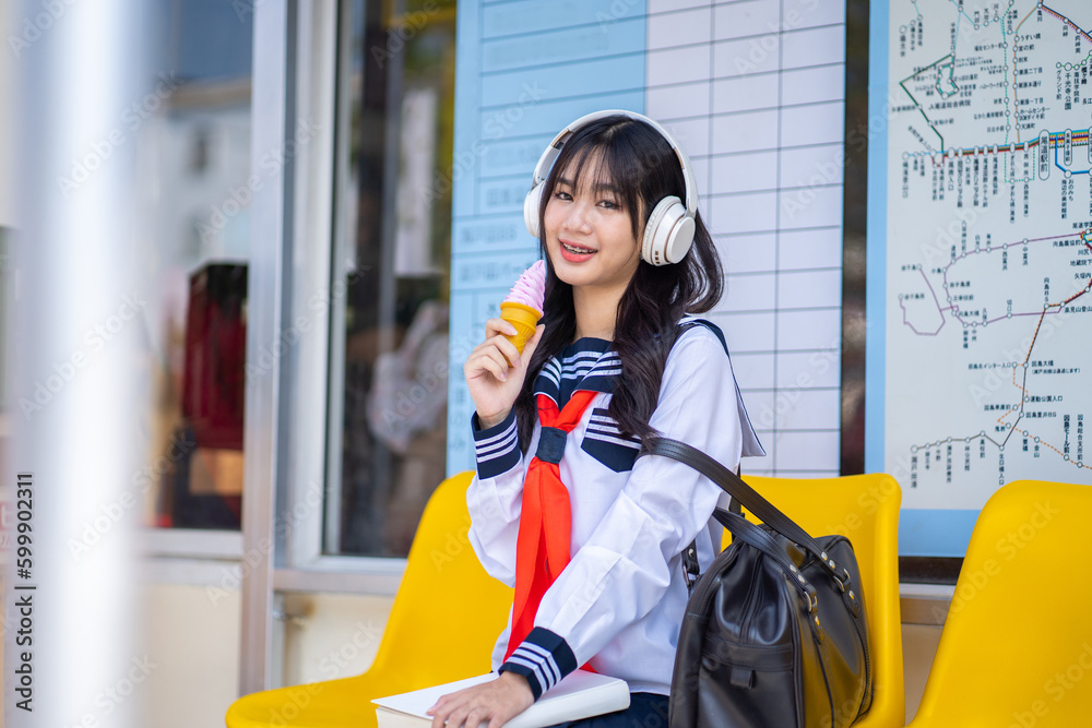 Portrait of a happy japanese school girl listening to music via ...