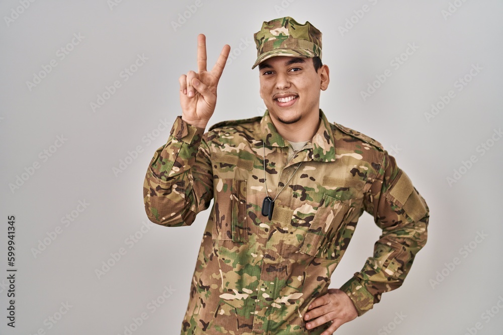 Young arab man wearing camouflage army uniform smiling looking to the ...