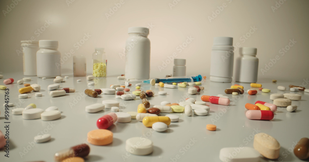 Colorful pills and tablets falling on white table with different types ...