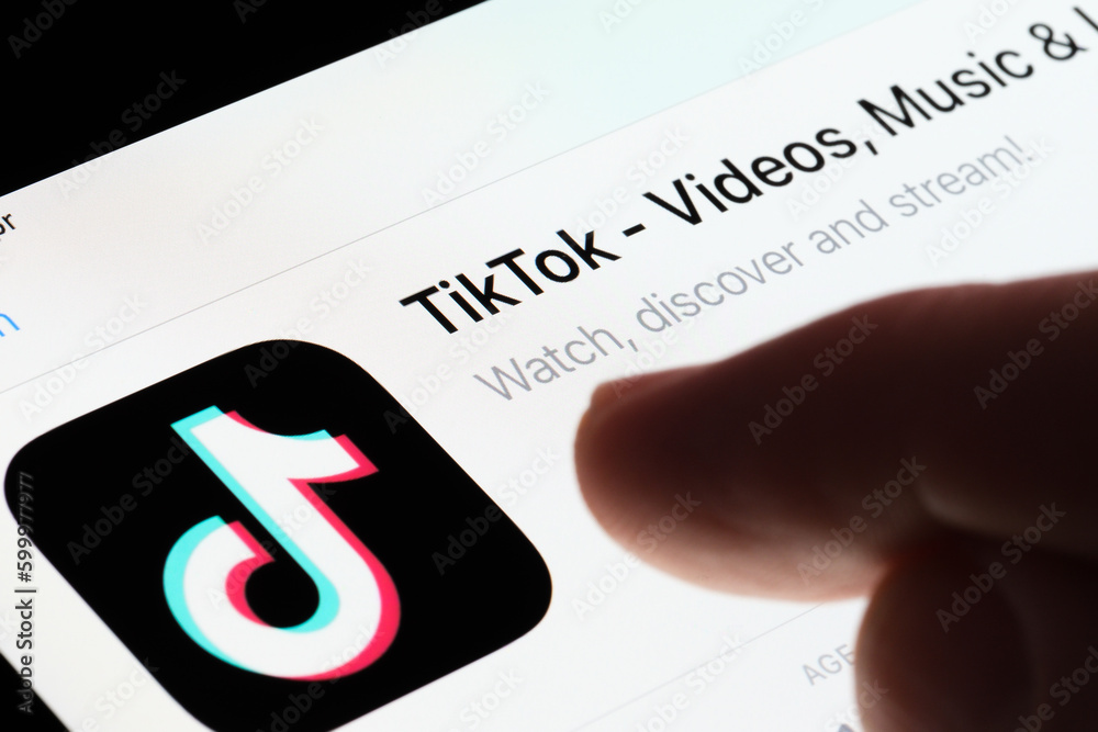 TikTok app seen in App Store on the screen of ipad and blurred finger ...