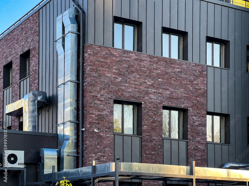 Modern dark red brick factory building exterior with steel air ducts on ...