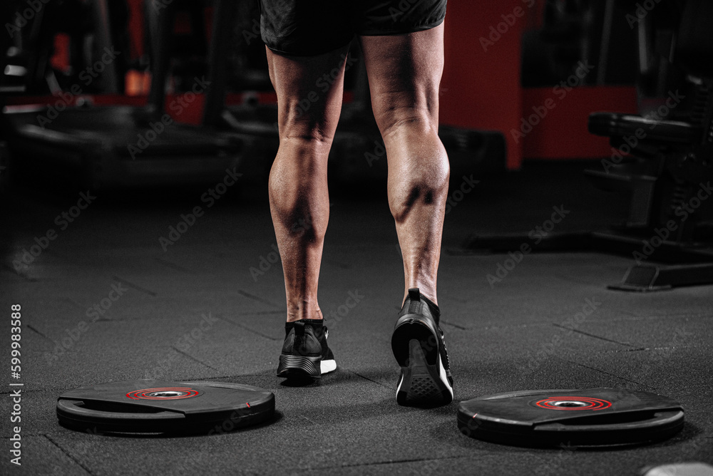 Trained man's legs with muscular calves in sneakers in fitness training ...