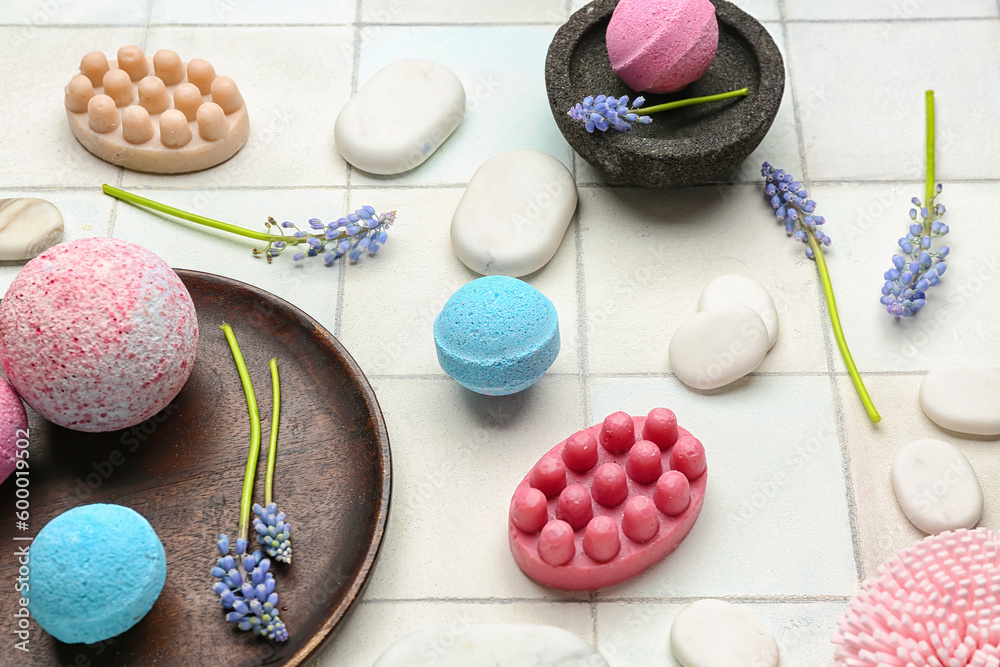 Bath bombs with flowers, soap bars and spa stones on white tile ...