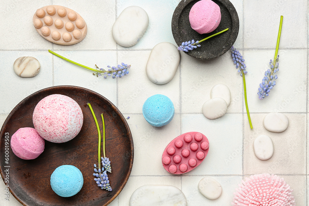 Bath bombs with flowers, soap bars and spa stones on white tile ...
