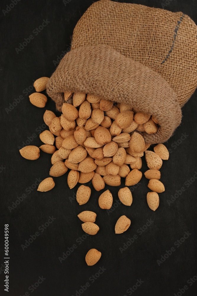 Almonds in a bag, on a black background, nuts in shell on the table ...