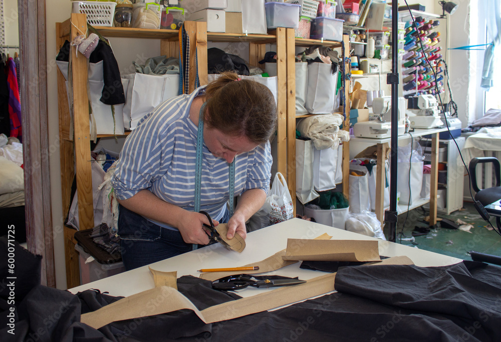 Professional seamstress creates a pattern for clothes in the workshop ...