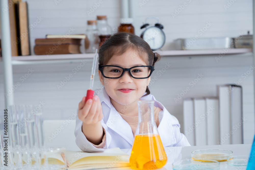 Cute little girl wearing lab coat learning chemistry in school ...
