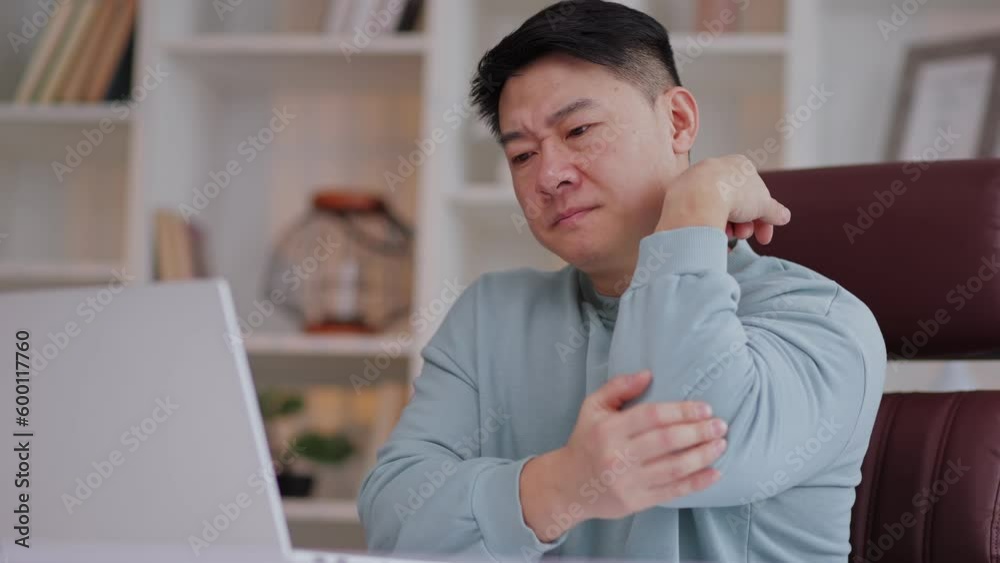 Pain in elbow. Asian man at computer workplace and experiencing pain ...