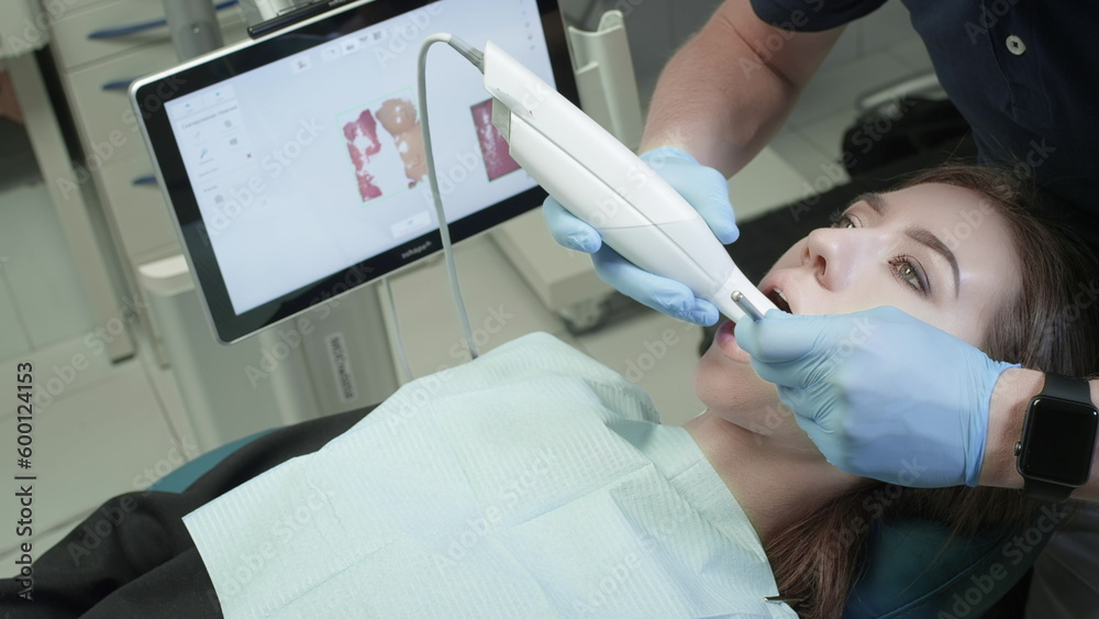 Doctor scans the patient's teeth in the clinic. The dentist holds in ...