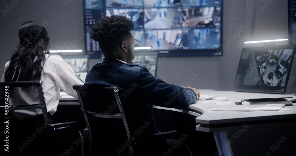 African American security operator monitors CCTV cameras with AI face ...